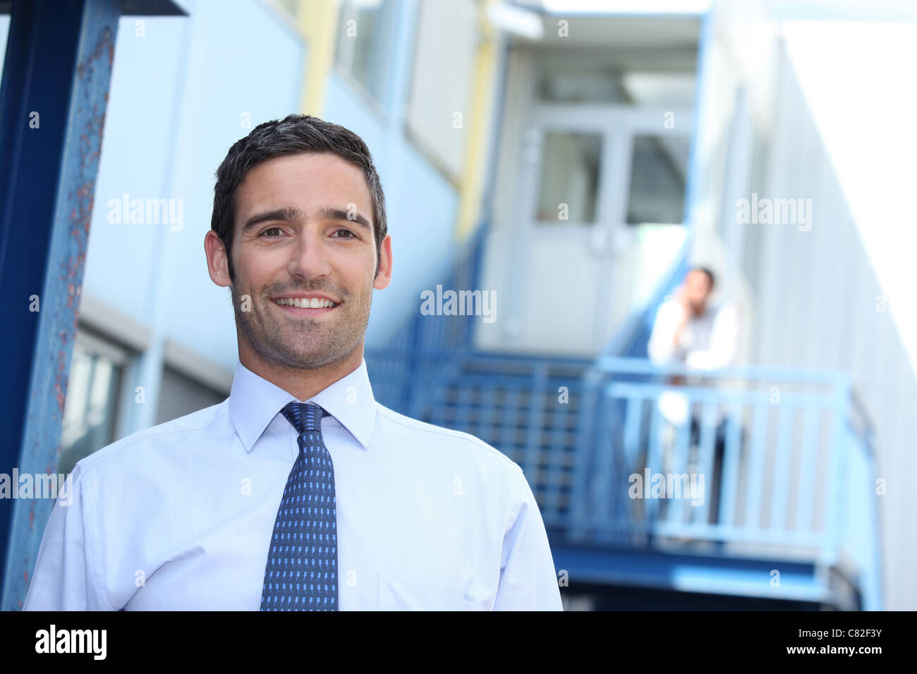 Businessman standing outside an office building Stock Photo - Alamy
