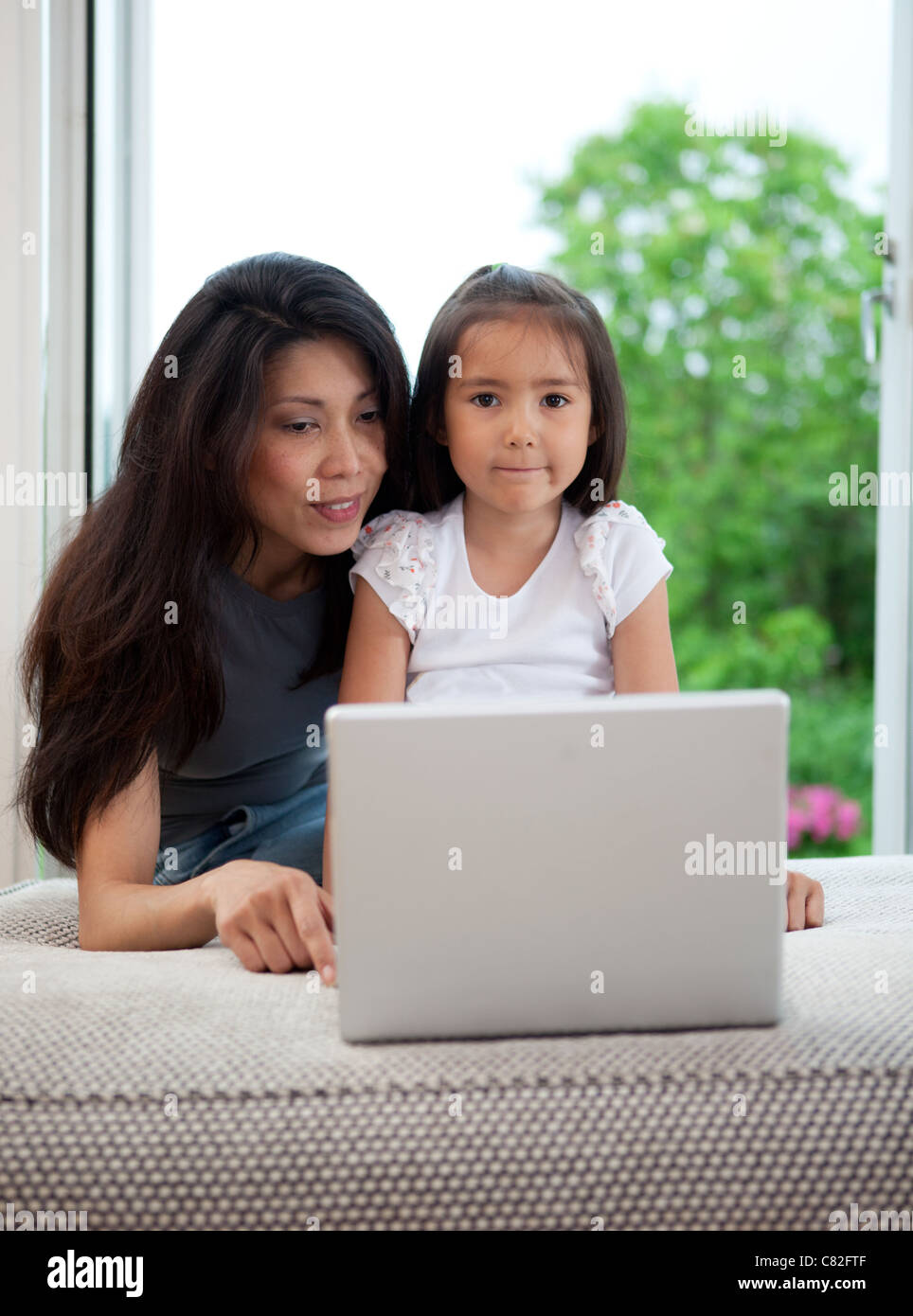 Mother and daughter using computer together in a home interior Stock ...