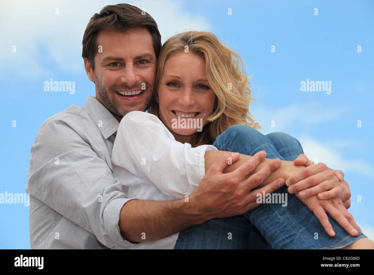 Couple sat hugging each other in park Stock Photo - Alamy