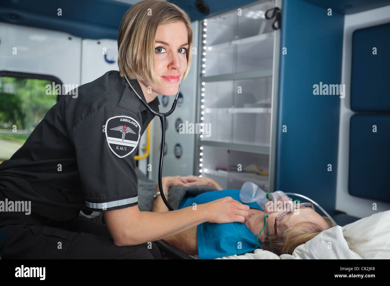 Portrait of a happy EMT worker inside ambulance tending to senior woman ...