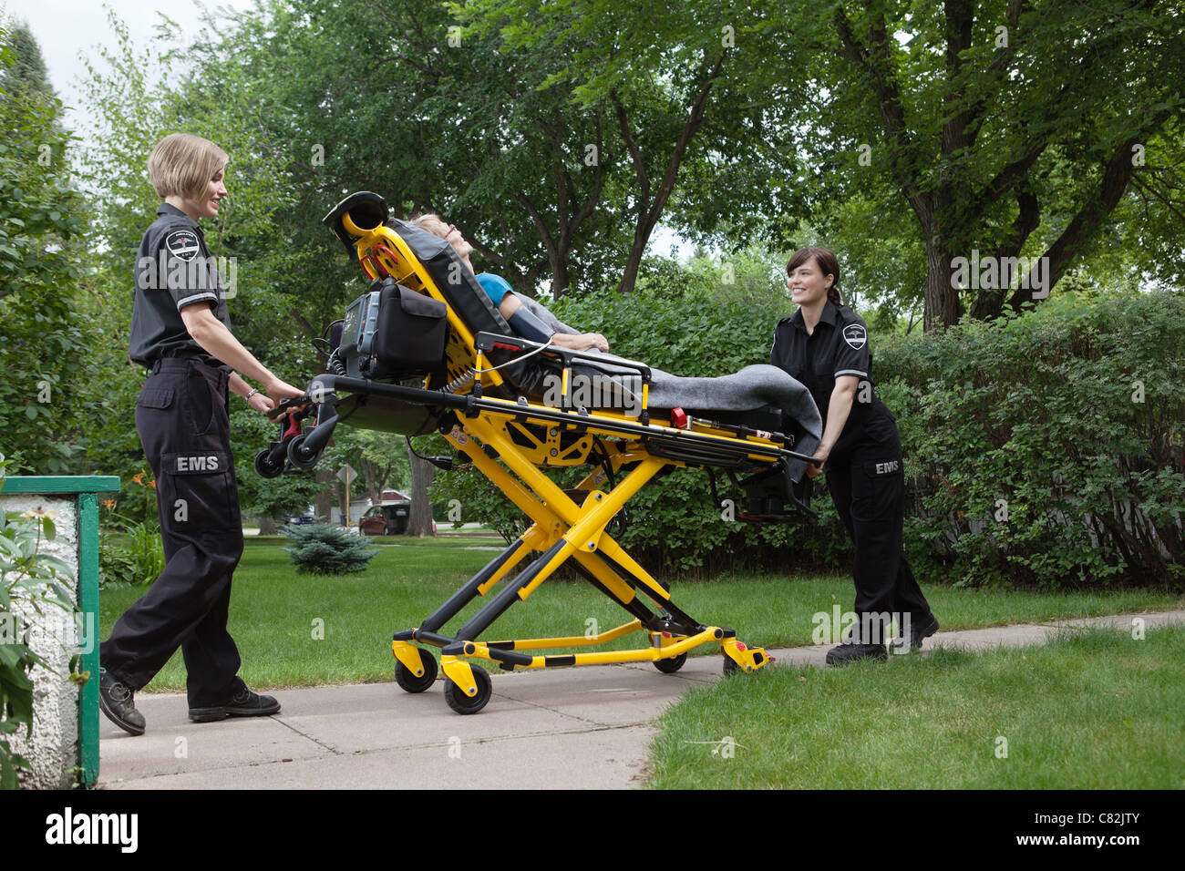 Female emergency medical team transporting senior patient on stretcher ...