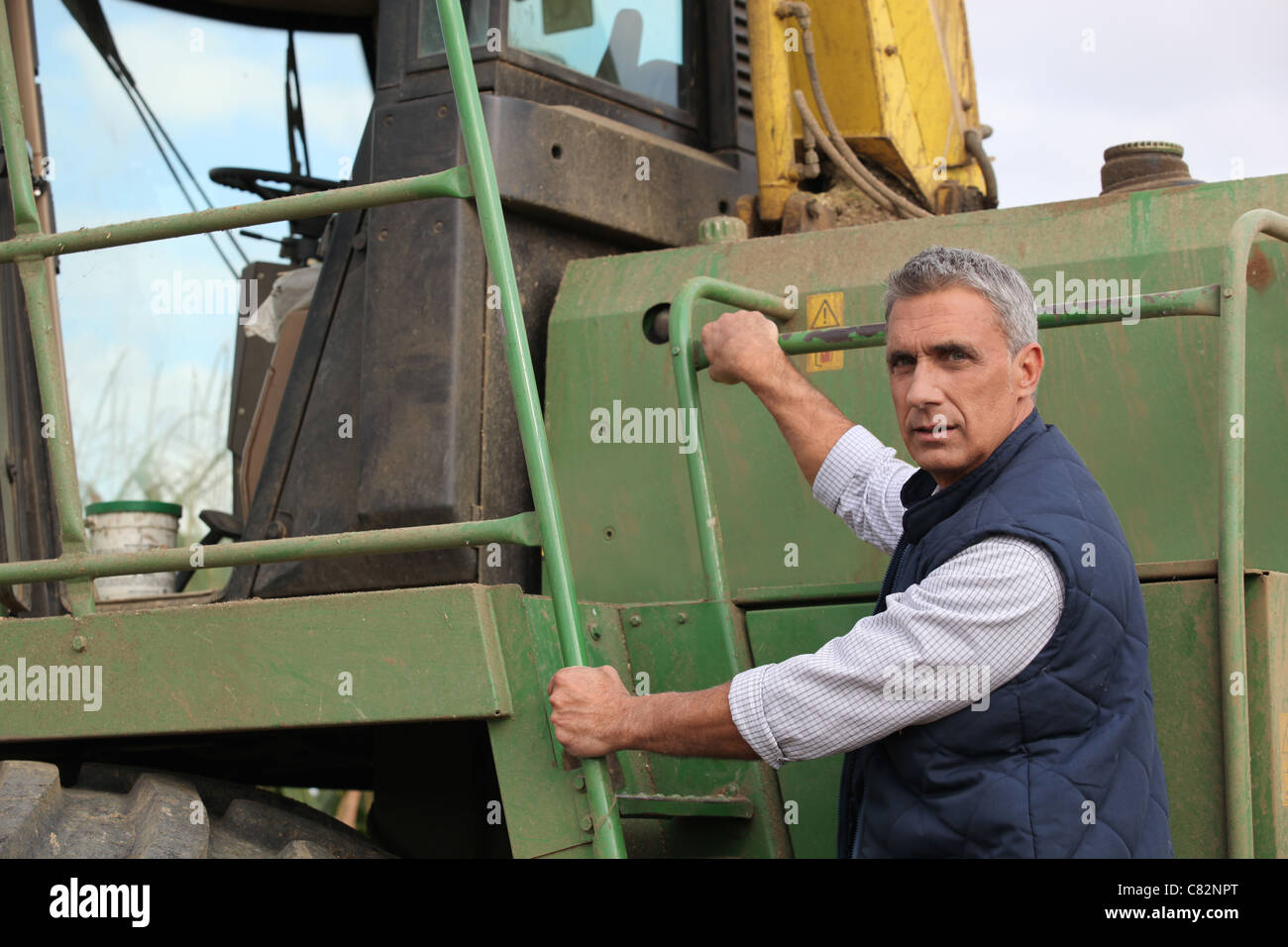 Farmer getting into tractor Stock Photo - Alamy