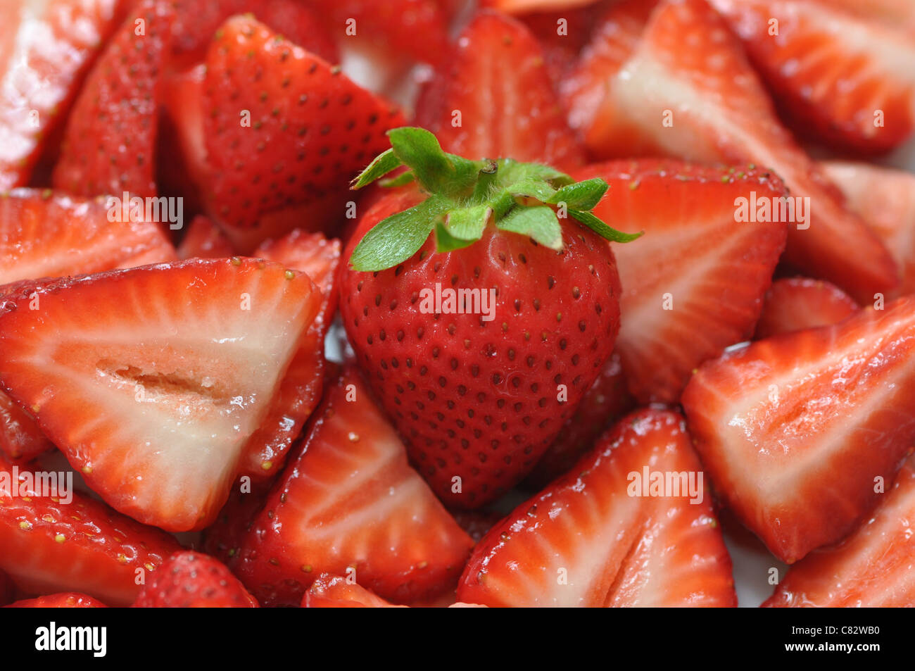 A single fresh strawberry on a bed of juicy strawberry slices Stock ...
