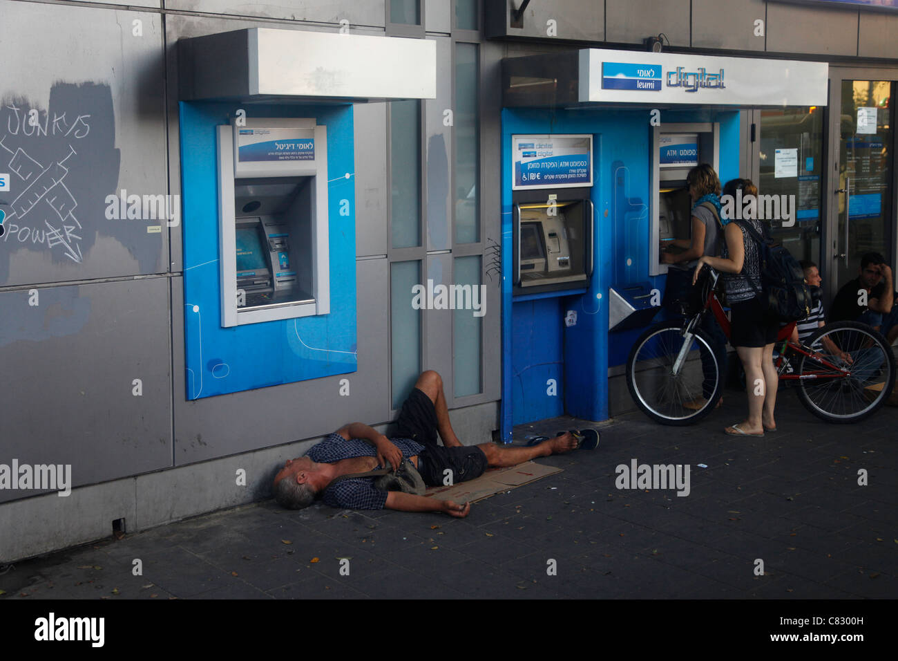 Israelis withdrawing money from ATM machine of bank Leumi as a homeless ...