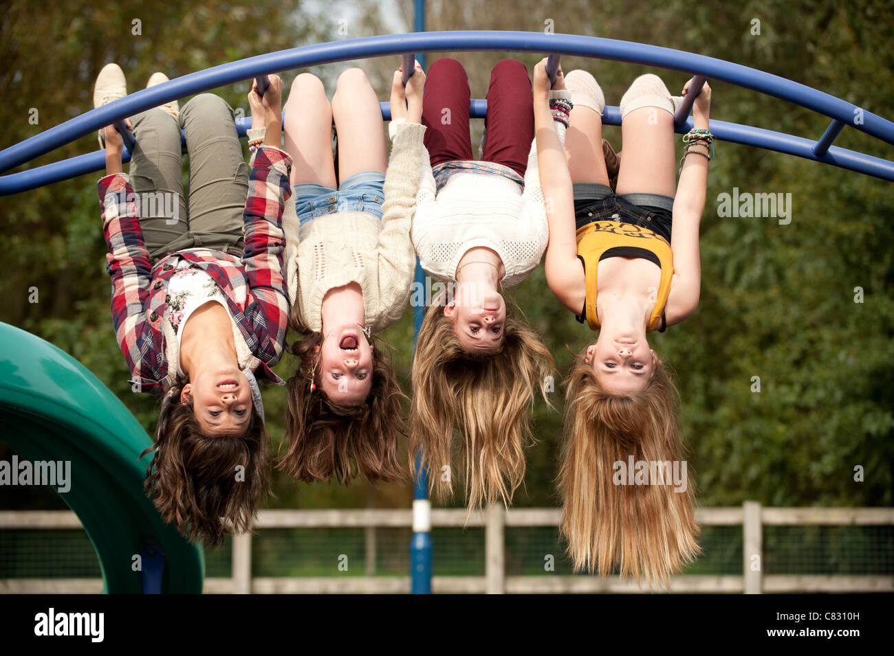 A group of 13 year old teenage girls having fun hanging upside down in a playground UK Stock ...