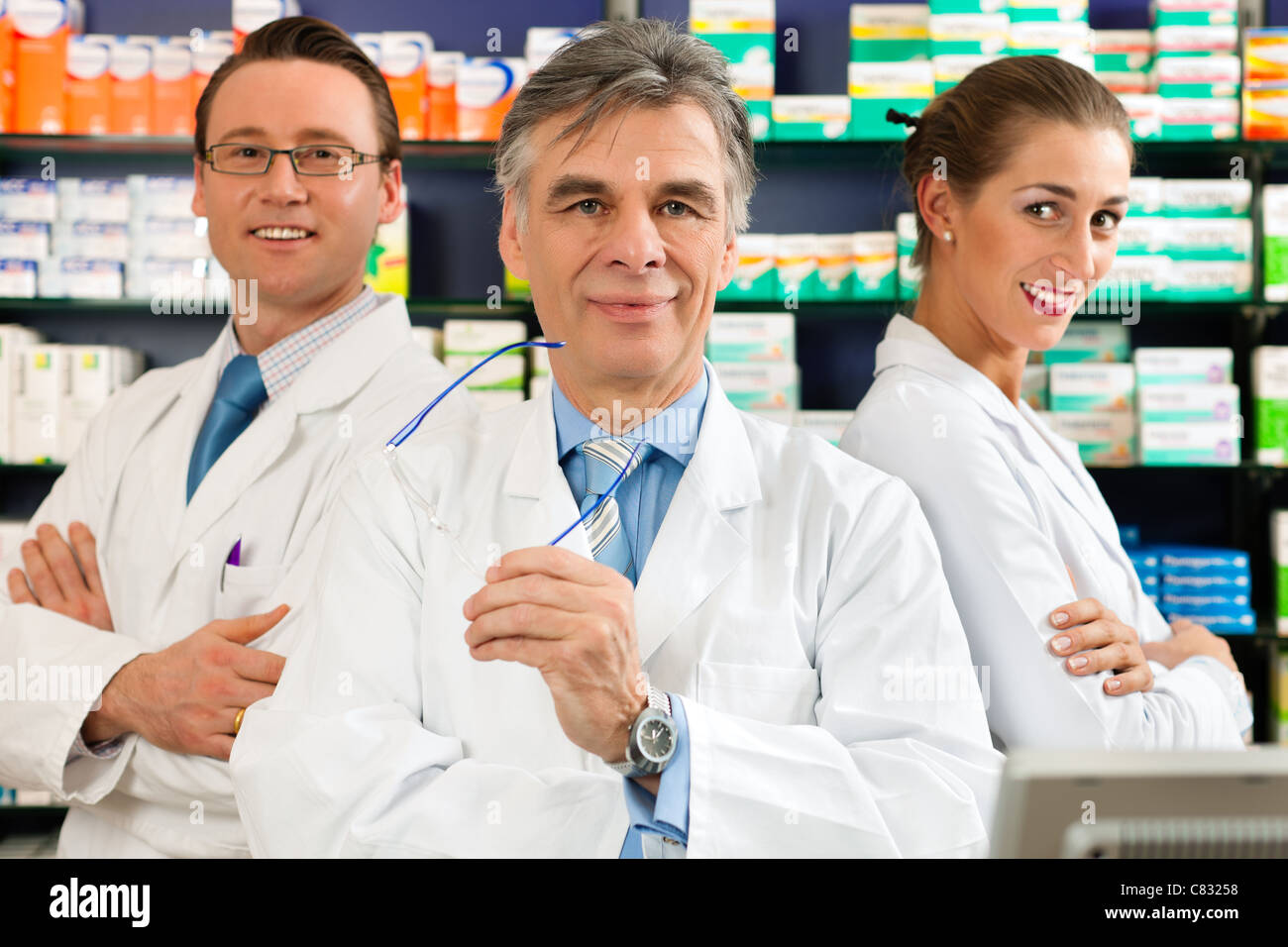 Pharmacist with his team standing in pharmacy or drugstore in front of ...