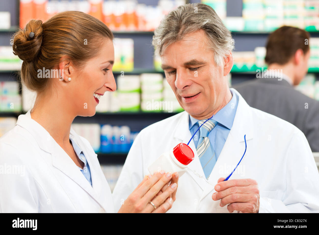 Two pharmacists with pharmaceuticals in hand consulting each other in a ...