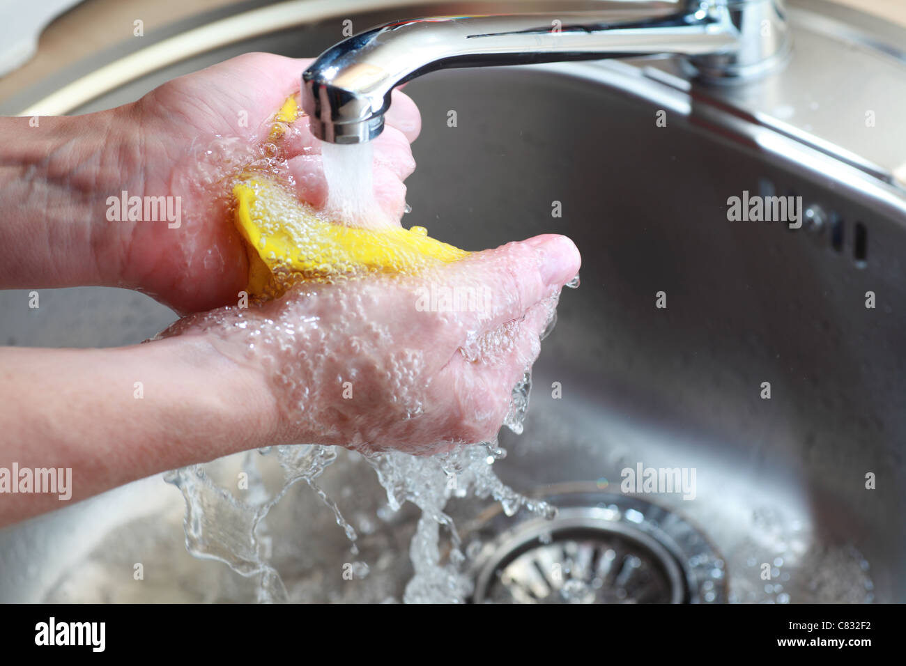 yellow cloth and hands under running water Stock Photo - Alamy