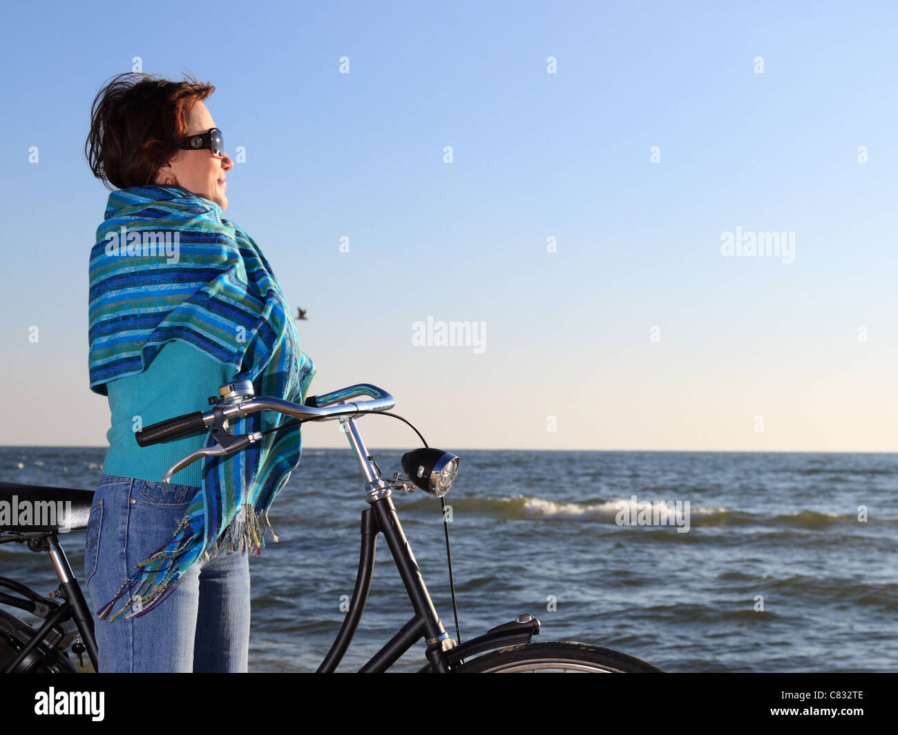 woman in blue, bike and shawl at sea shore Stock Photo - Alamy