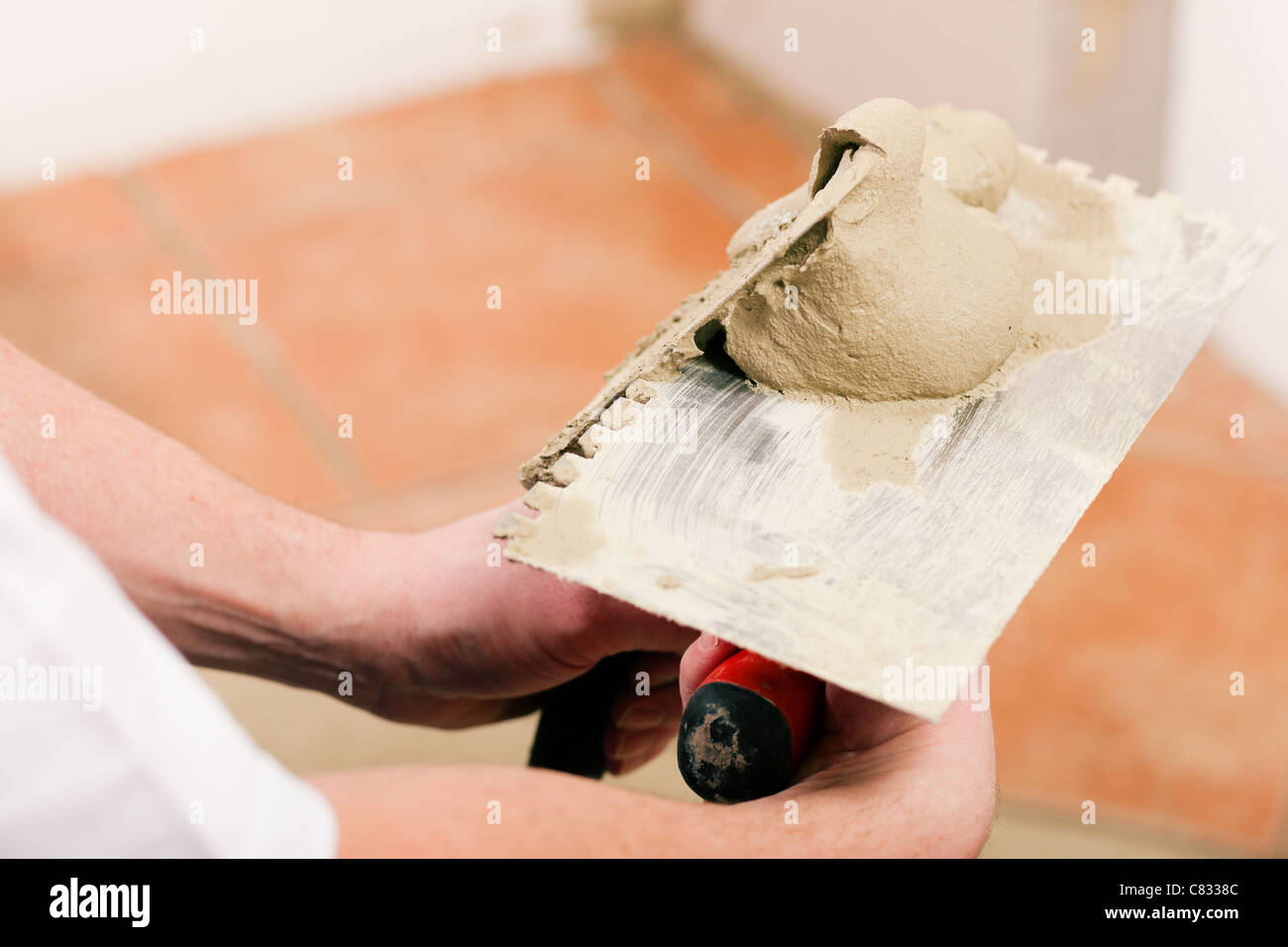 Construction worker is tiling at home Stock Photo - Alamy