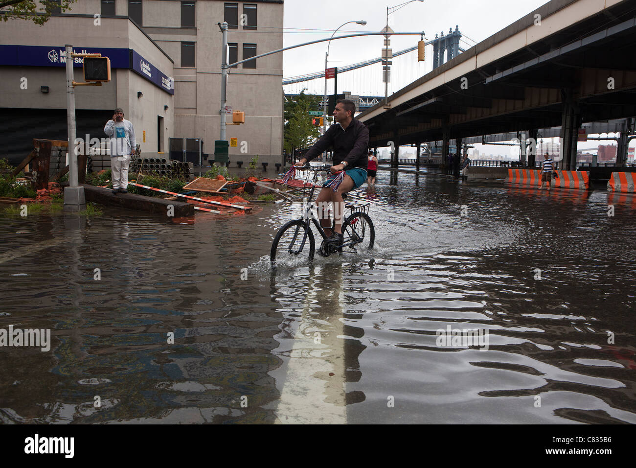 Biker on flooded street under Manhattan Bridge, NYC, during hurricane ...