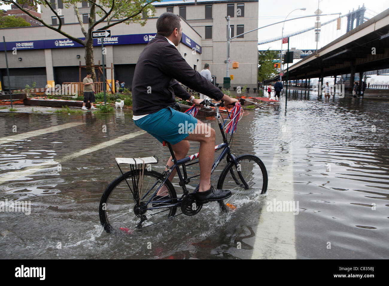 Biker on flooded street under Manhattan Bridge, NYC, during hurricane ...