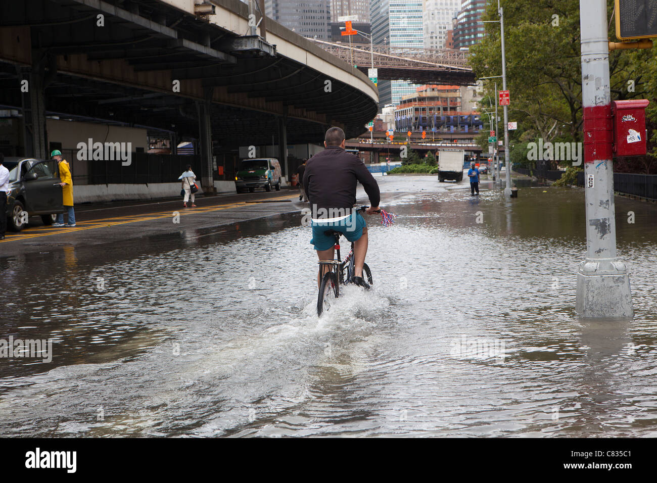 Biker on flooded street under Manhattan Bridge, NYC, during hurricane ...