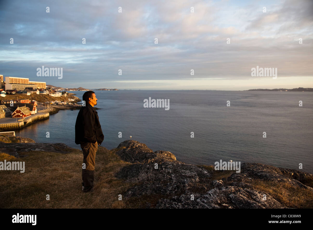 Greenlandic man over looks the old Harbour, Nuuk, 19th June 2009, two ...