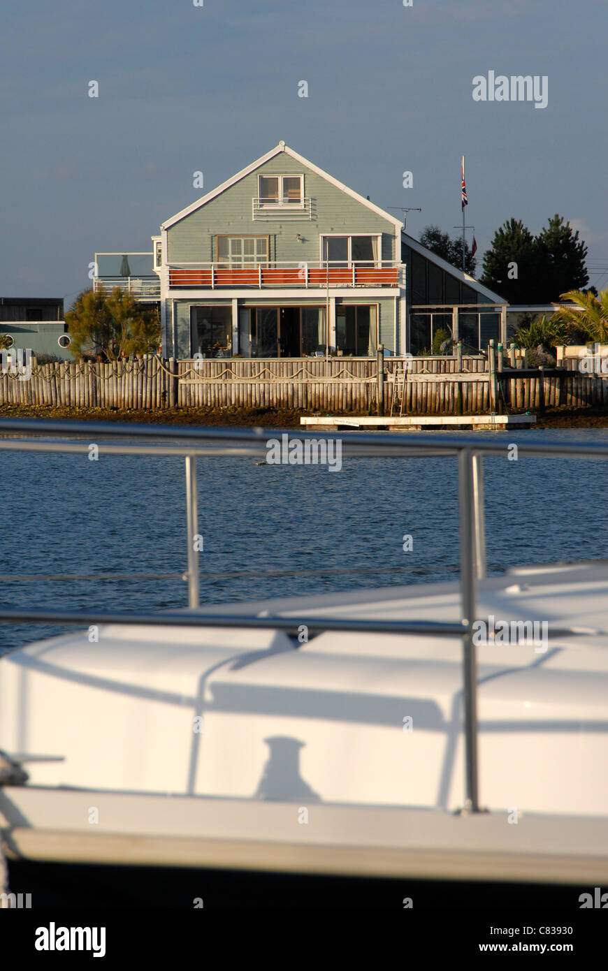 Waterside house in evening sunlight across water Stock Photo - Alamy