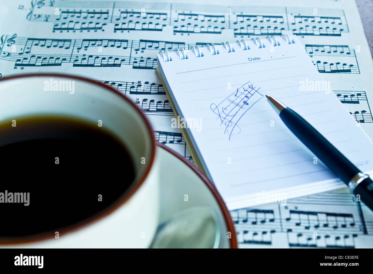 Cafee in cup on background music note and score note with black pen ...