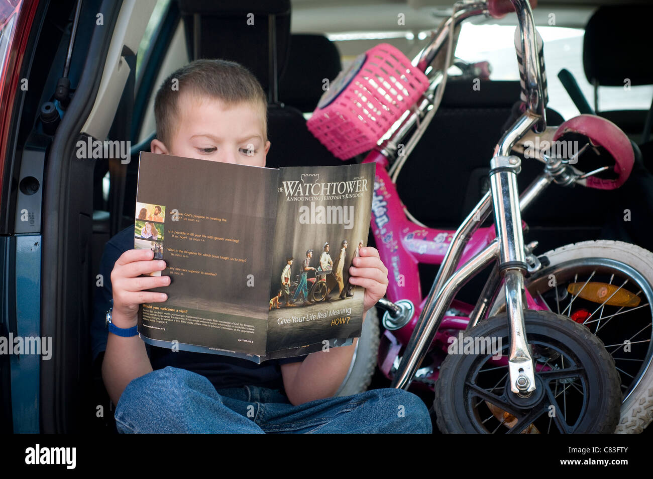 young boy reading the watchtower magazine in back of family car,young ...