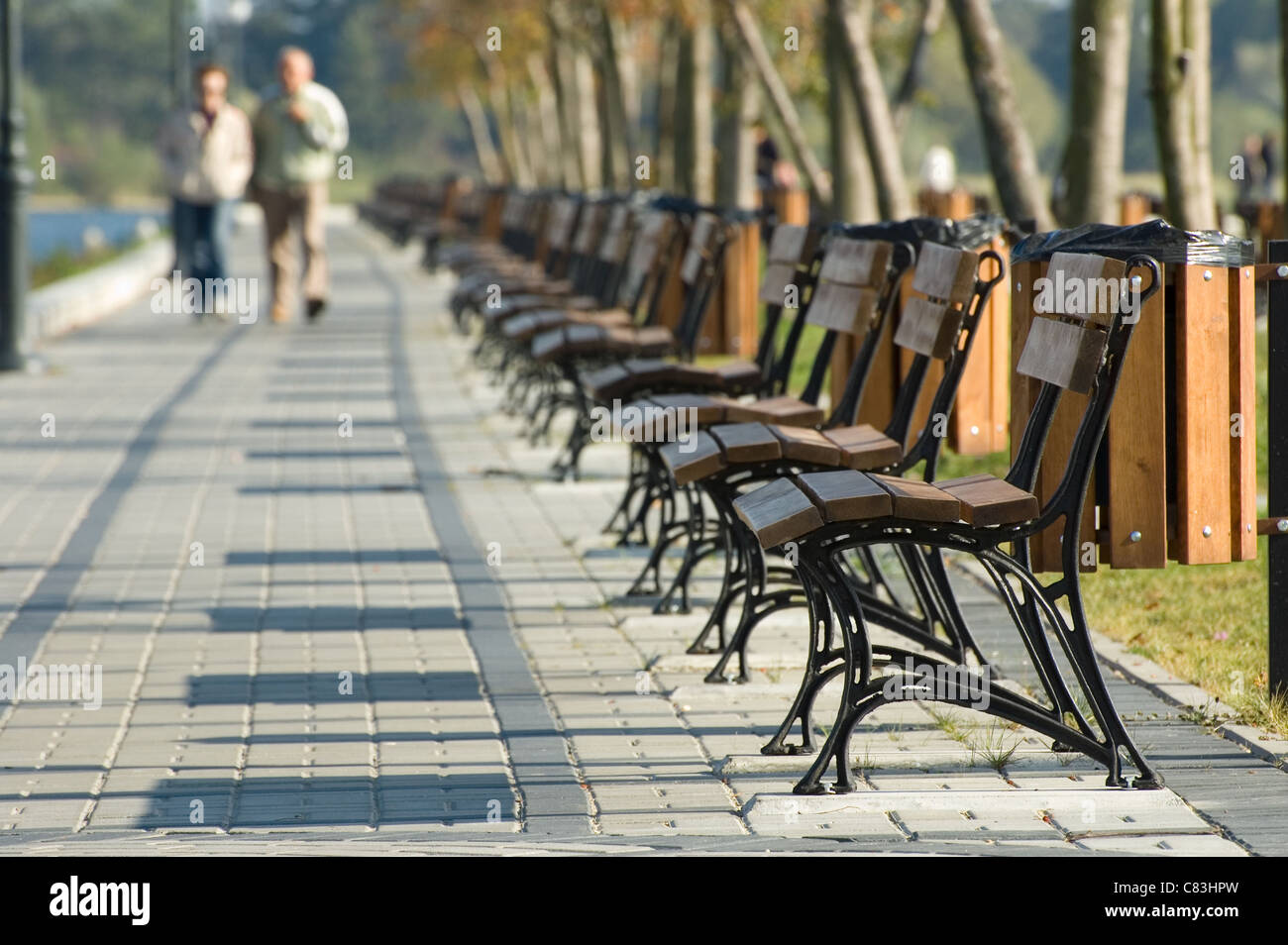 People walking along bench row Stock Photo - Alamy