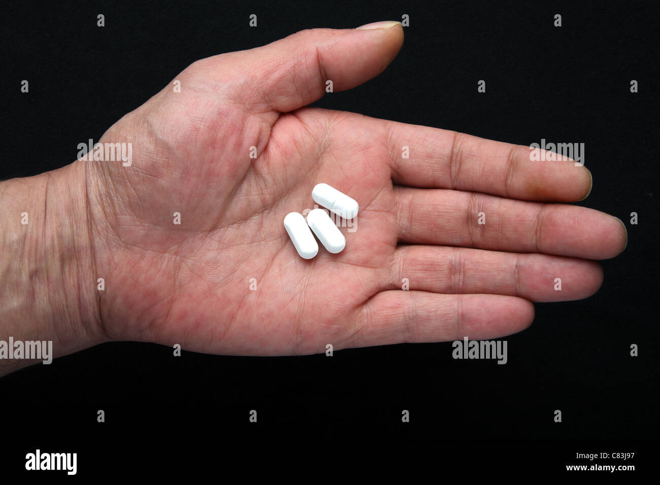 Three pills on a hand Stock Photo - Alamy