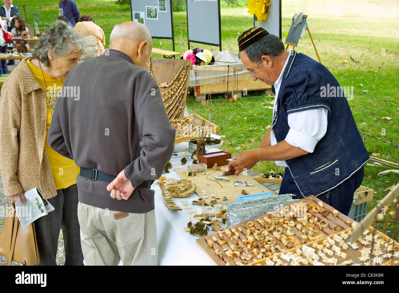 Craftsman in Swiss national dress shows carvings to customers at an ...