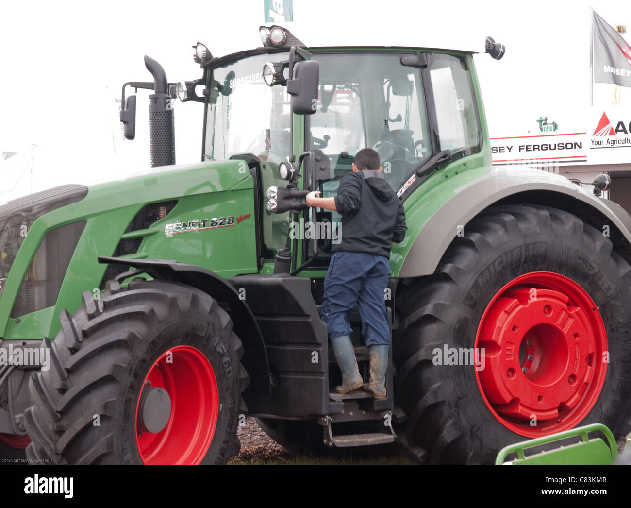 YOUTH LOOKING INTO THE CAB OF A BIG GREEN TRACTOR Stock Photo - Alamy