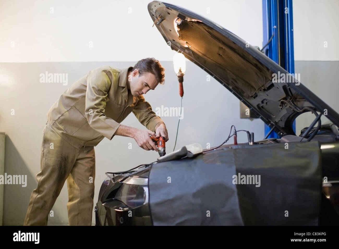 Mechanic working on car engine in garage Stock Photo - Alamy