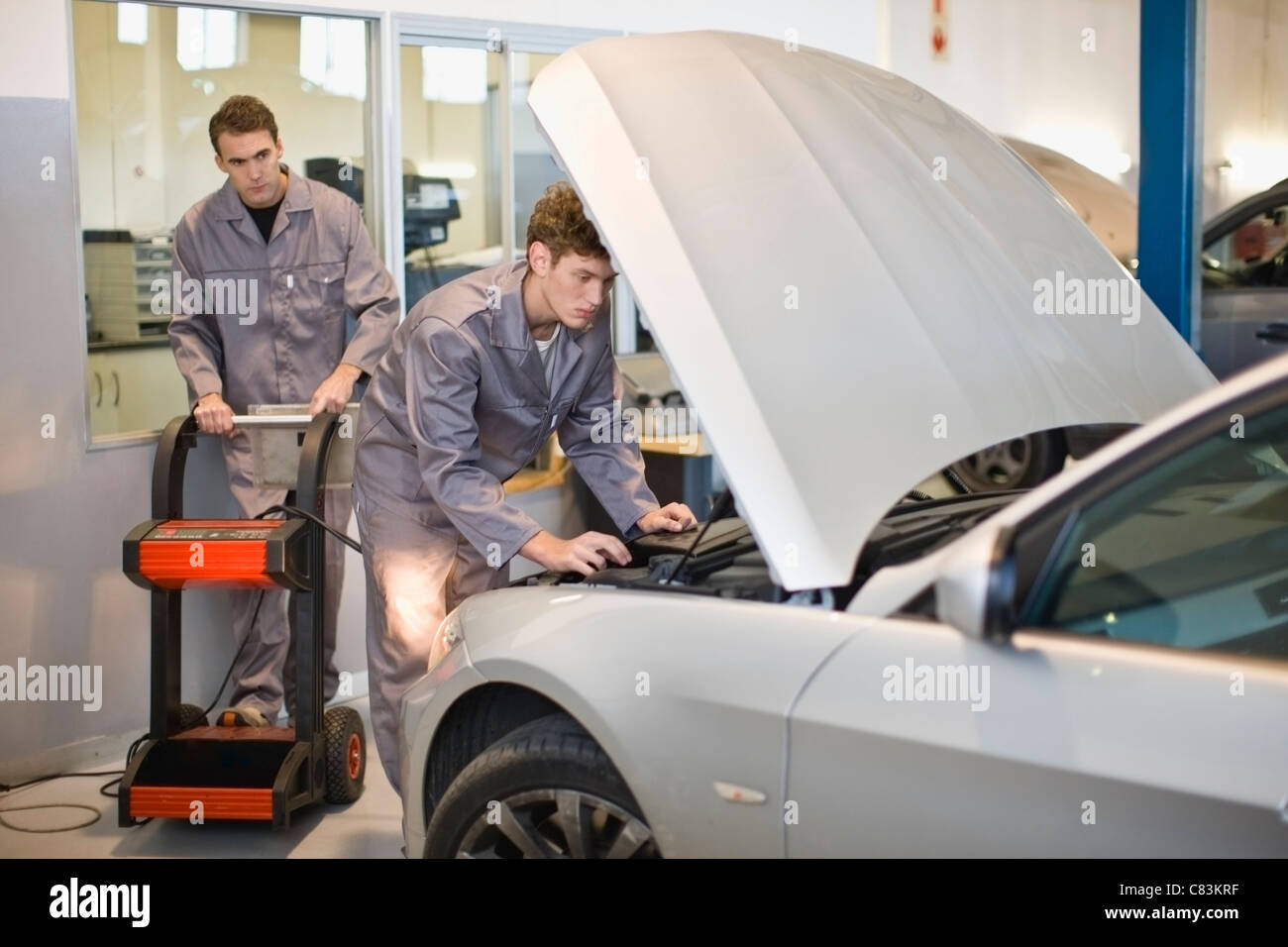 Mechanics working on car engine Stock Photo - Alamy