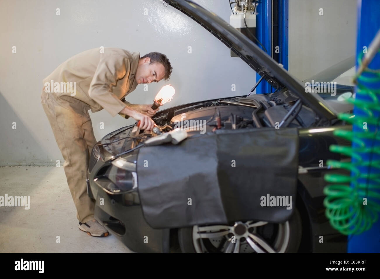 Mechanic working on car engine in garage Stock Photo - Alamy