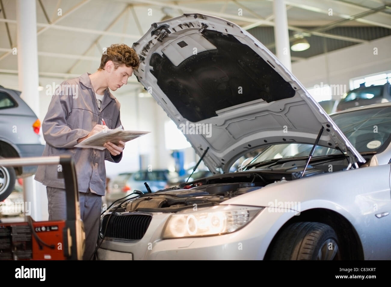 Mechanic examining car engine in garage Stock Photo - Alamy