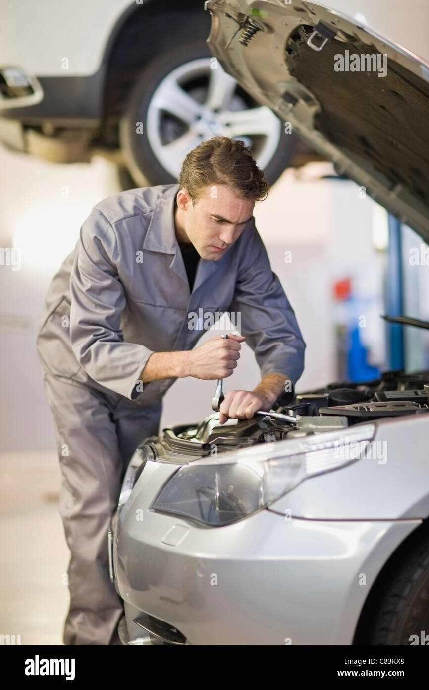 Mechanic working on car engine in garage Stock Photo - Alamy