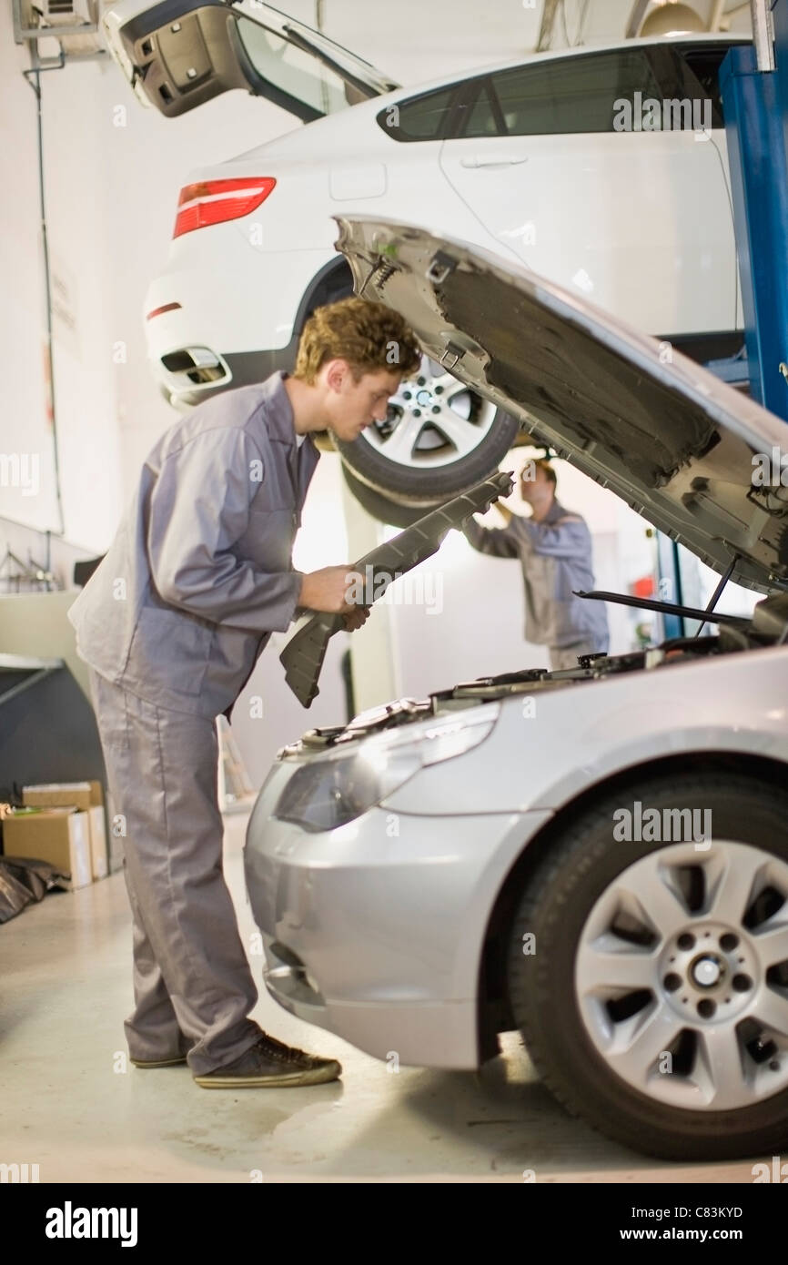 Mechanic working on car engine in garage Stock Photo - Alamy
