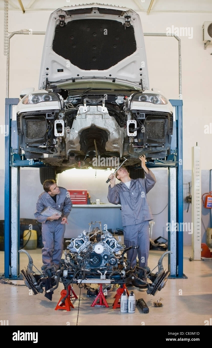 Mechanics working on car in garage Stock Photo - Alamy