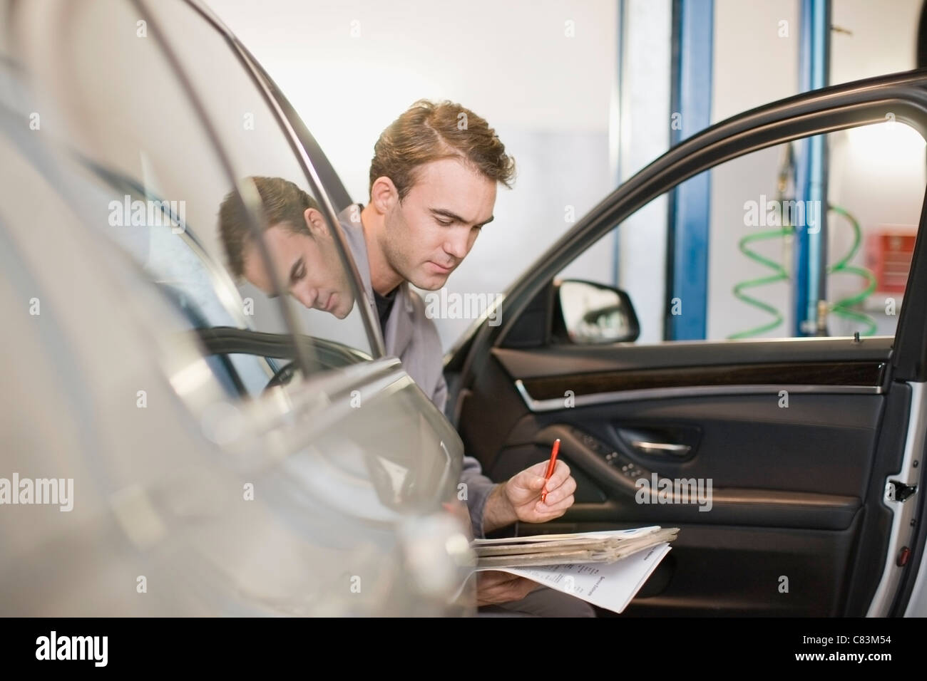 Mechanic examining car in garage Stock Photo - Alamy