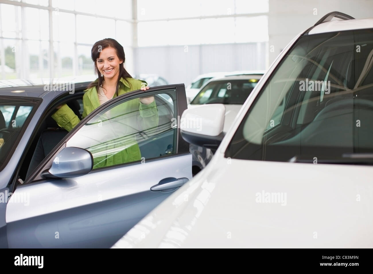 Woman climbing into car in showroom Stock Photo - Alamy