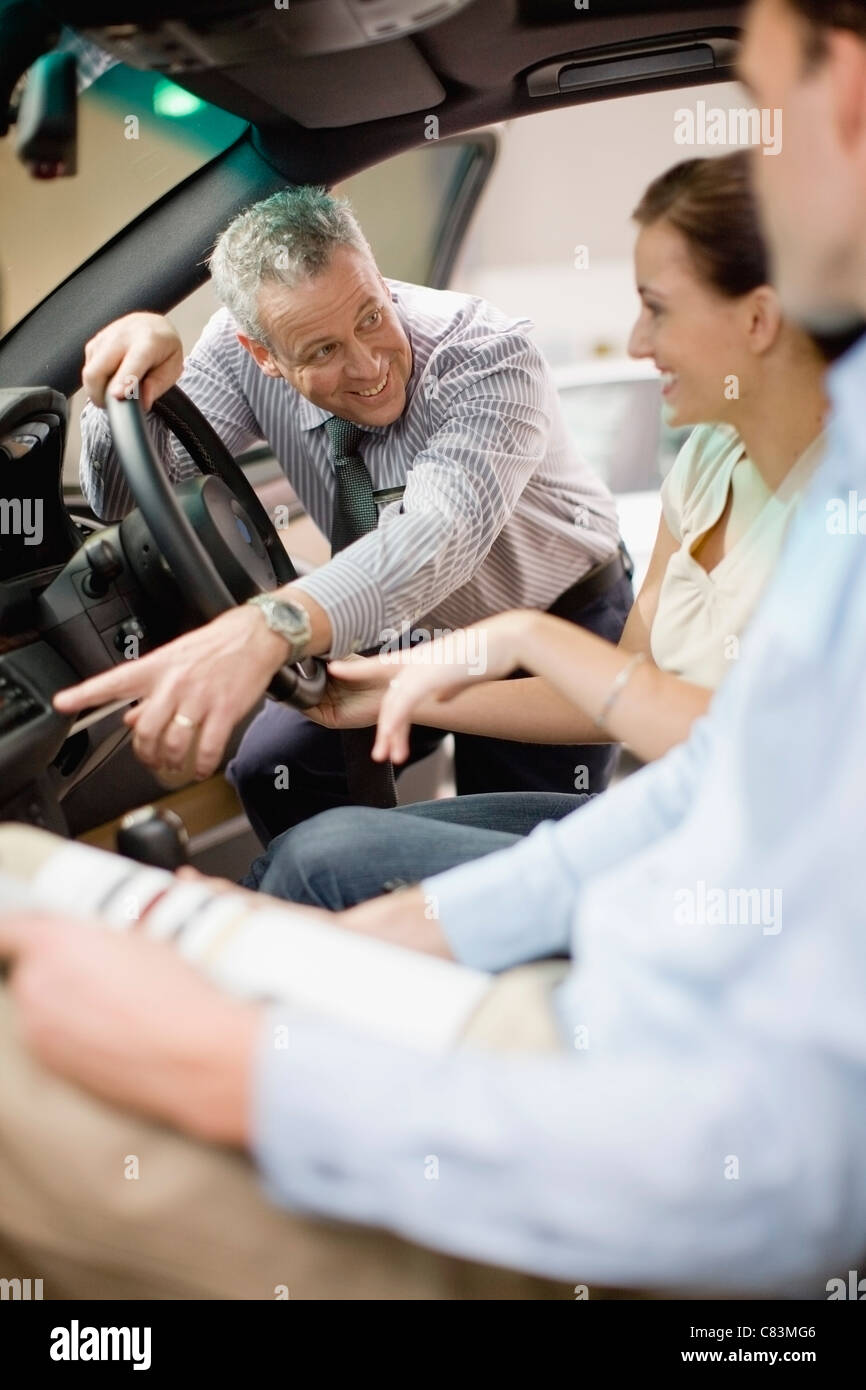 Salesman showing off car in showroom Stock Photo - Alamy