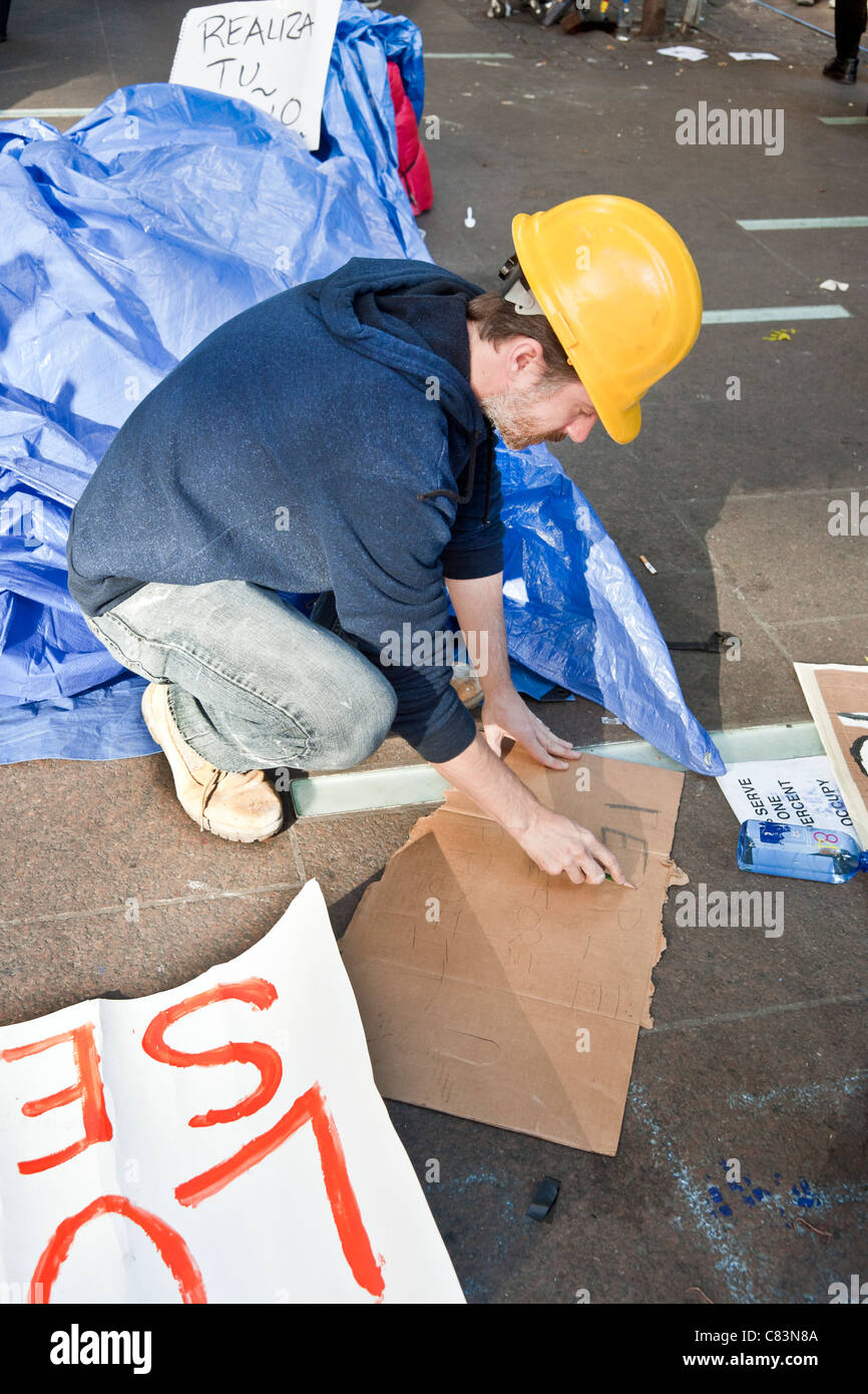construction worker intently lettering cardboard sign reading people ...