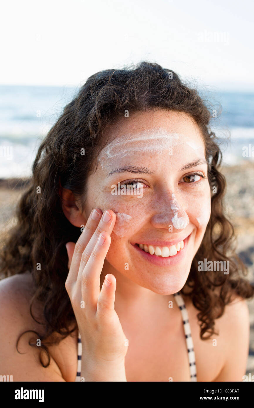 Smiling woman applying sunscreen to face Stock Photo - Alamy