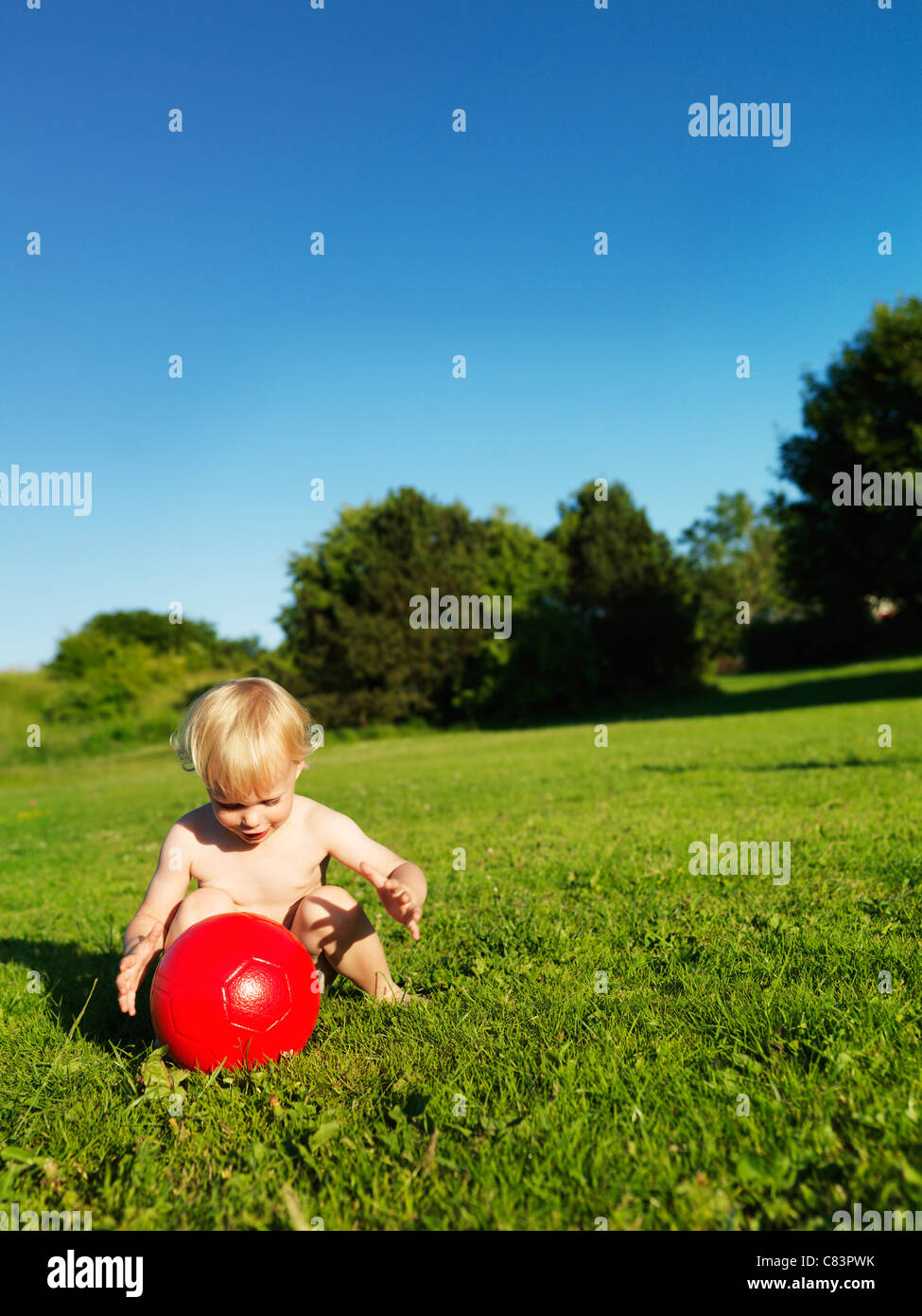 Toddler playing with red ball outdoors Stock Photo - Alamy