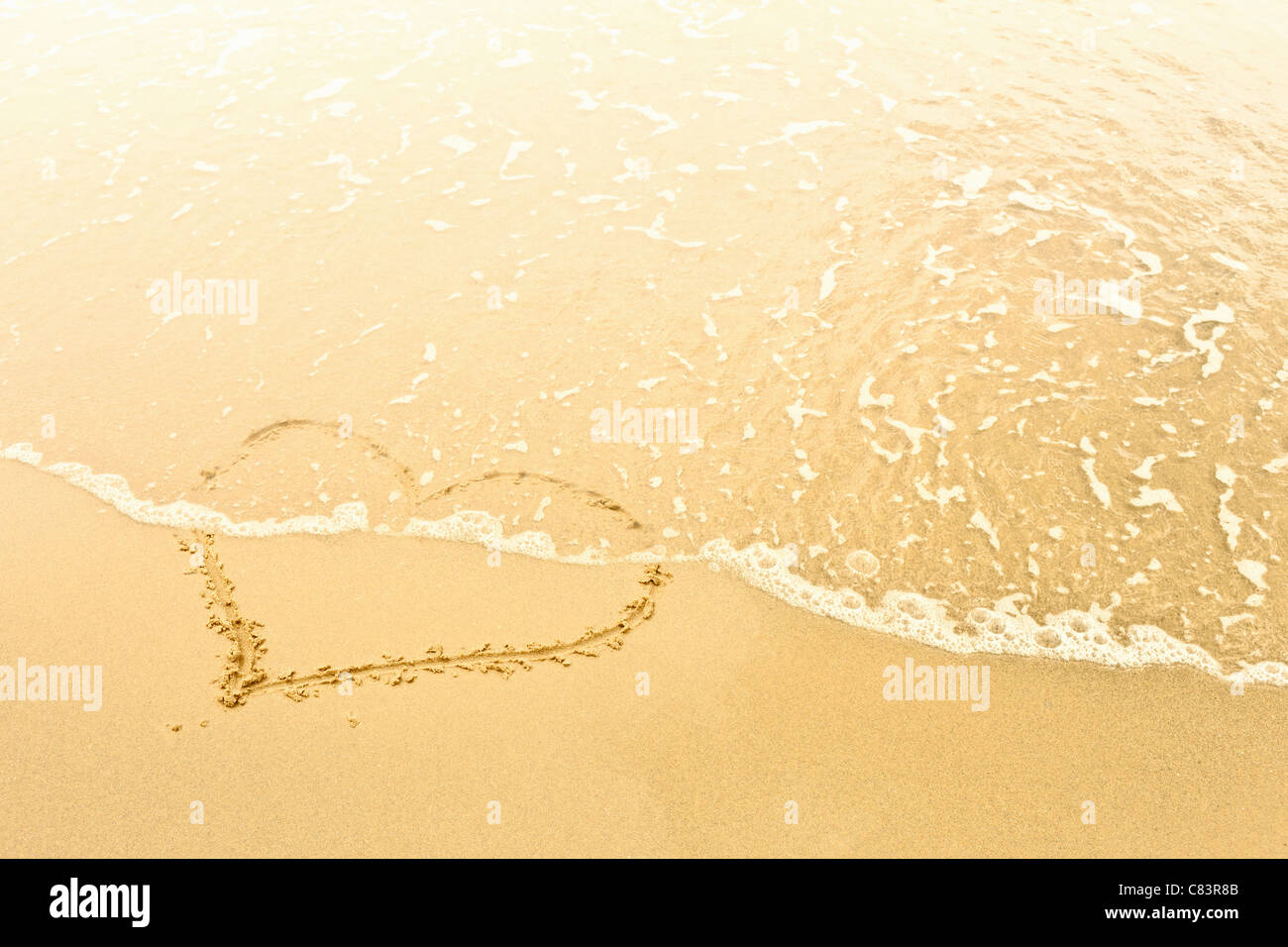 Heart in sand washed away by waves Stock Photo - Alamy