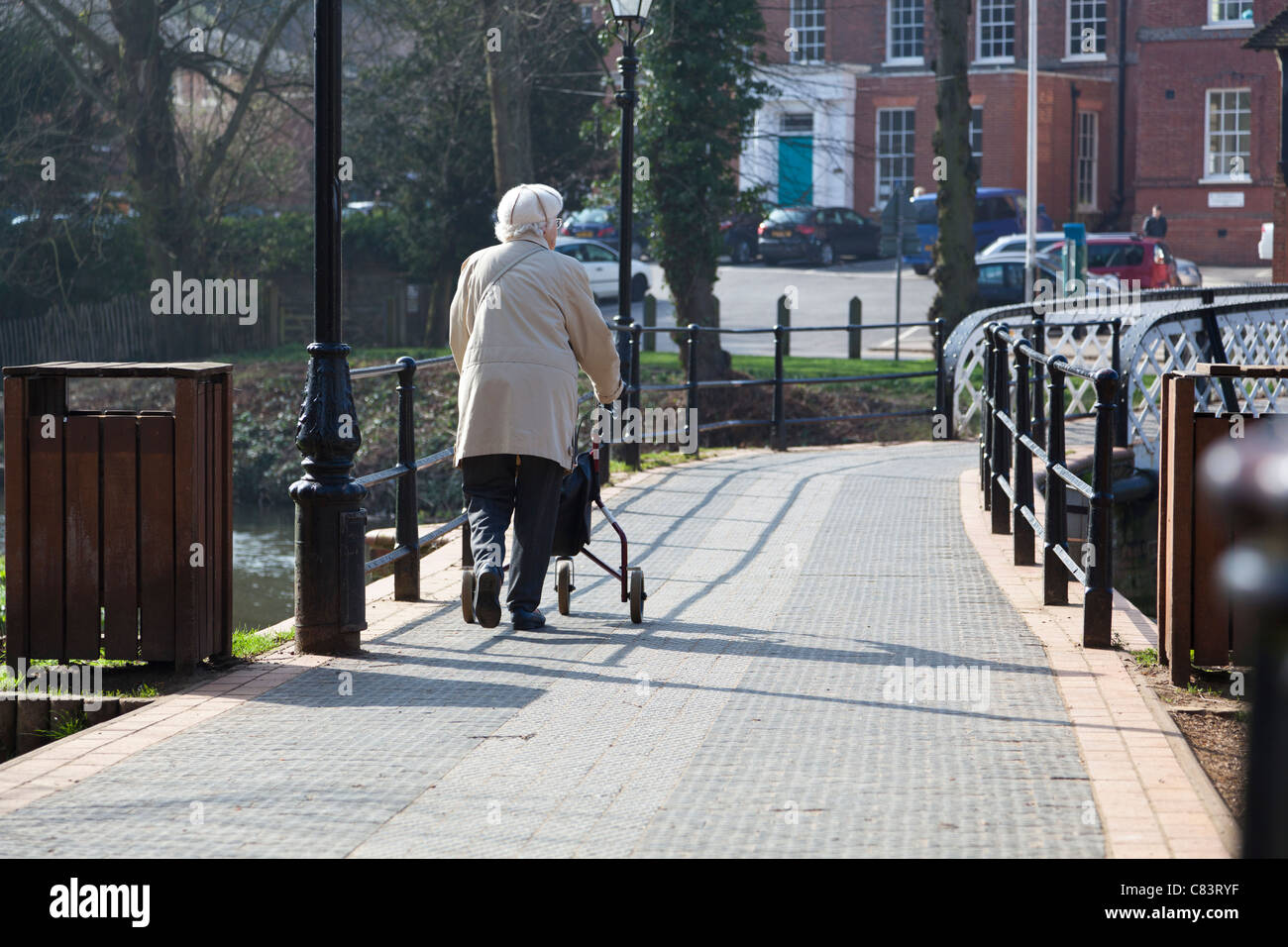 Elderly woman using a 3 wheeled walking frame Stock Photo - Alamy