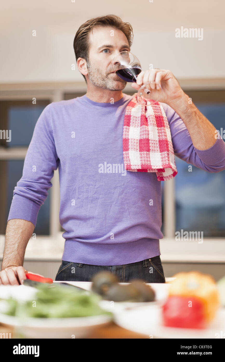 Man drinking wine and cooking dinner Stock Photo - Alamy