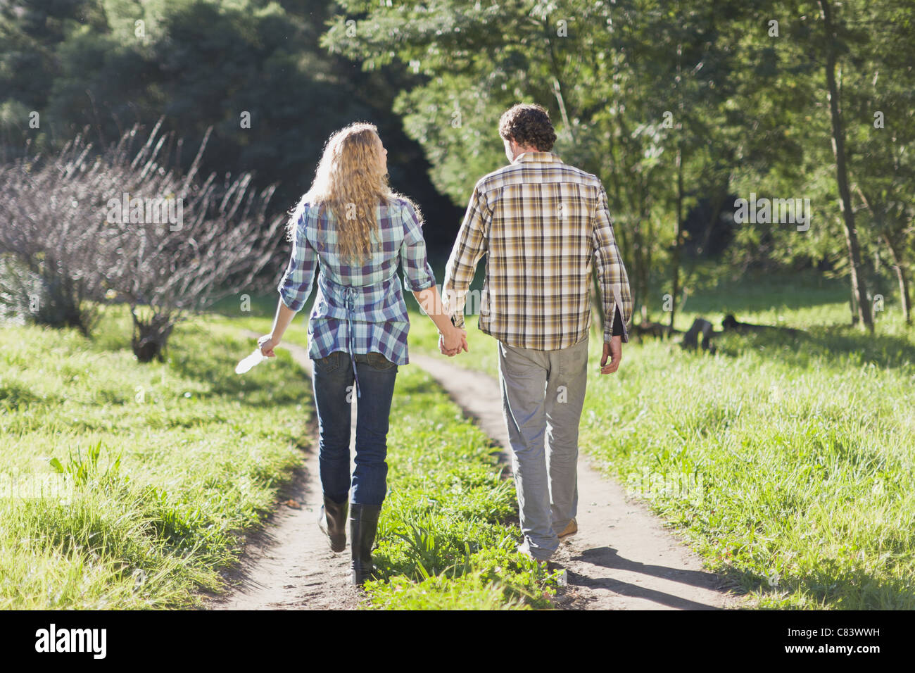 Couple walking hand-in-hand on dirt path Stock Photo - Alamy