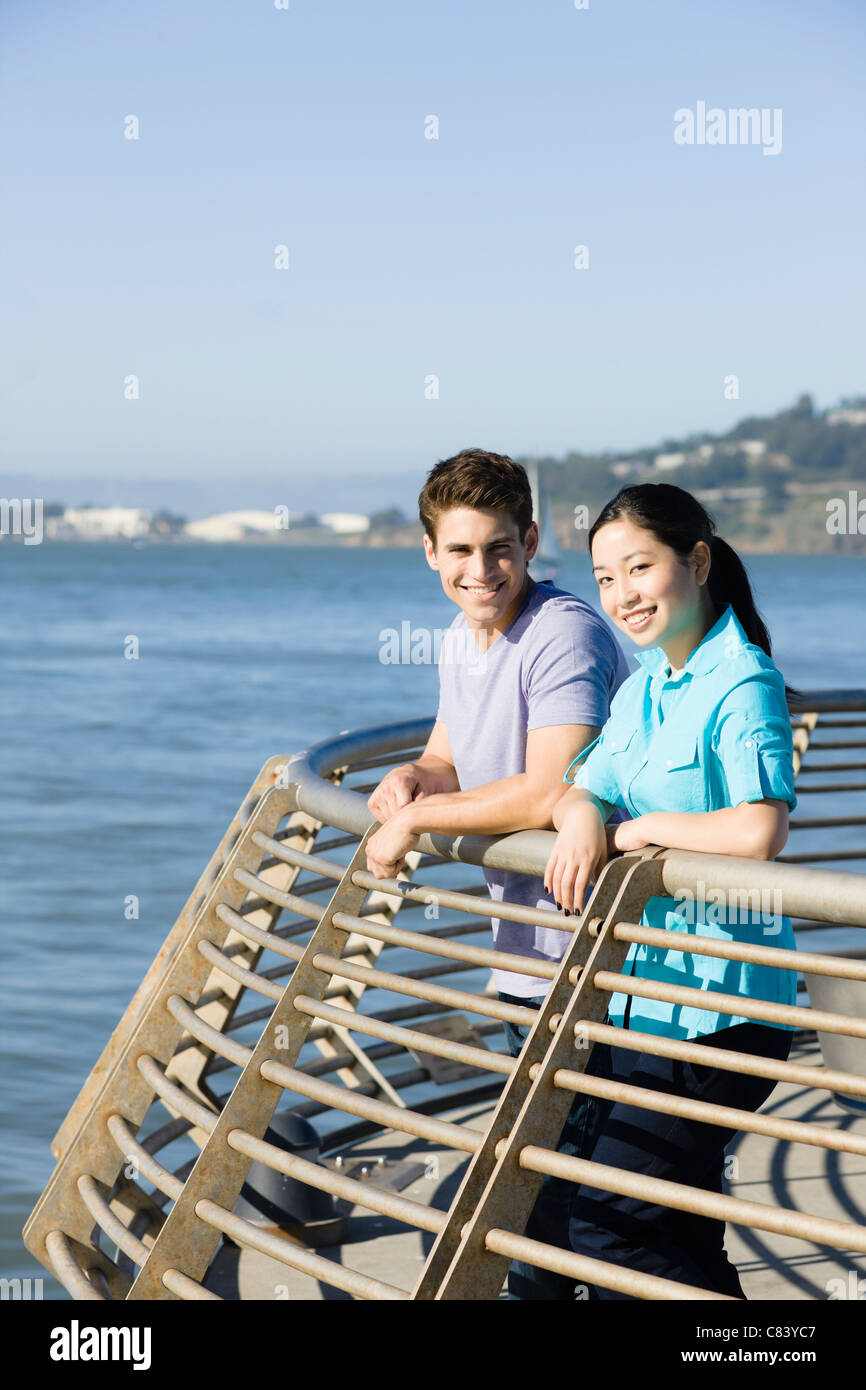 Couple leaning on railing at waterfront Stock Photo - Alamy