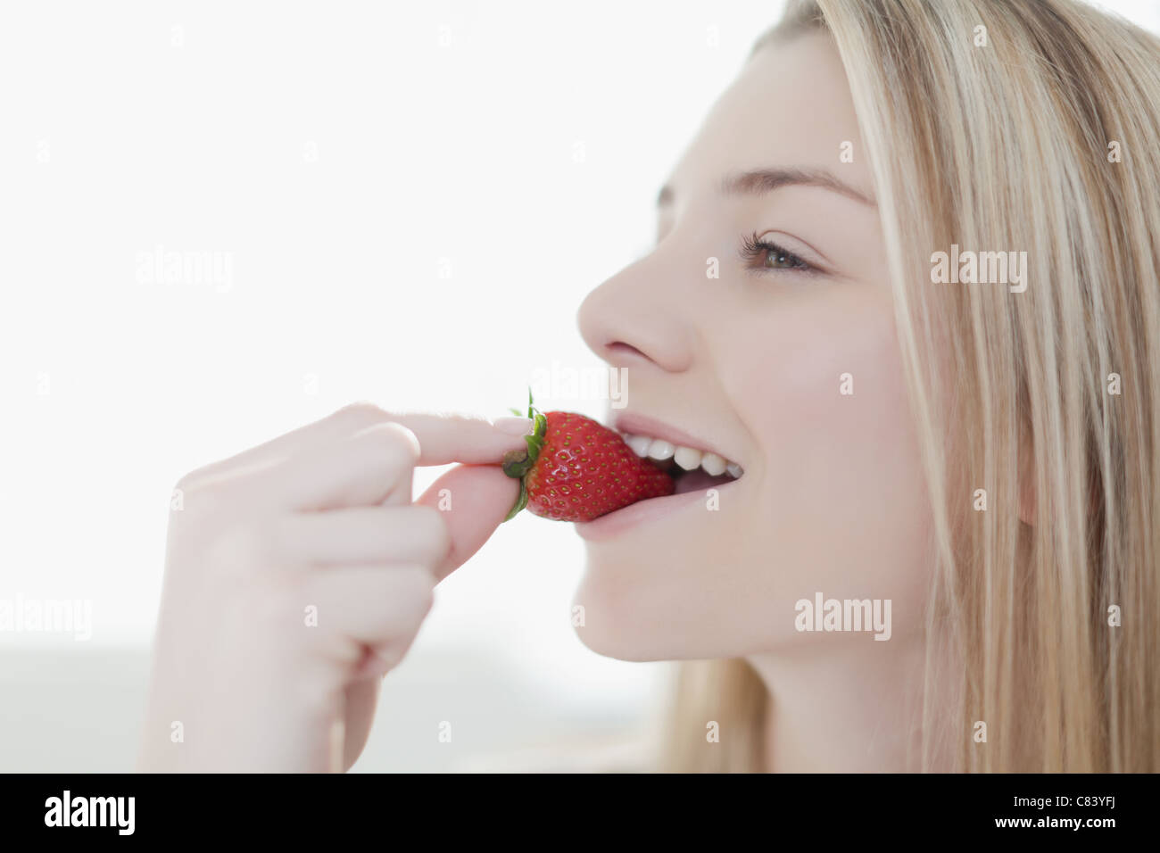 Smiling woman eating strawberry Stock Photo - Alamy