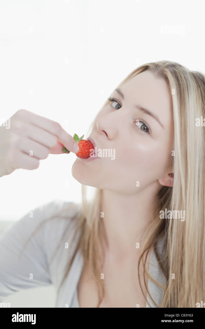Smiling woman eating strawberry Stock Photo - Alamy