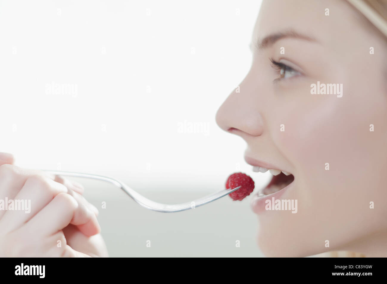Smiling woman eating raspberry Stock Photo - Alamy
