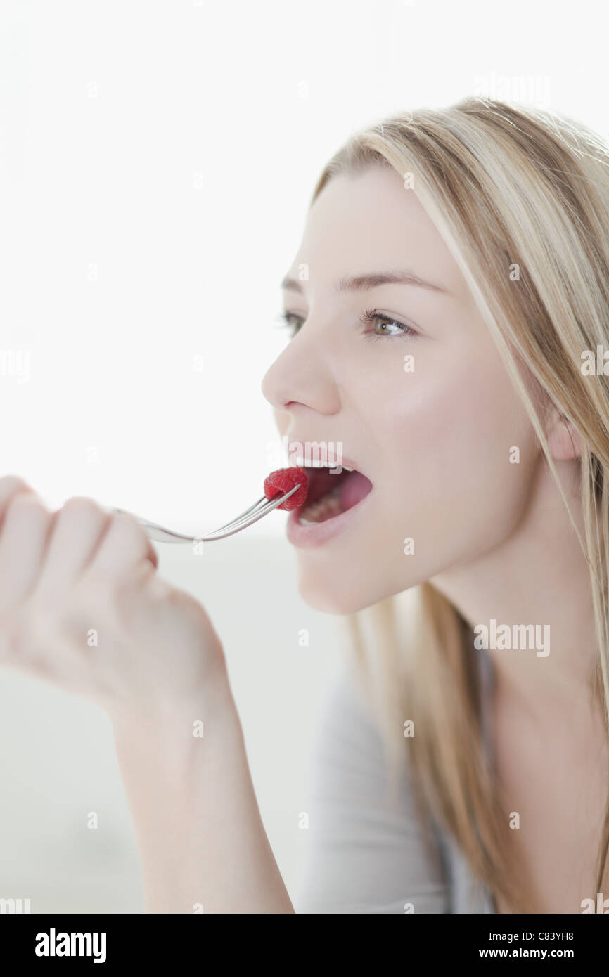 Smiling woman eating raspberry Stock Photo - Alamy