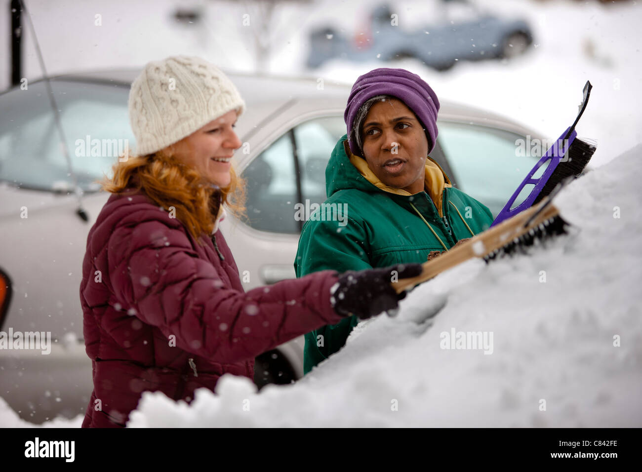 Two women scraping snow from windshield Stock Photo - Alamy