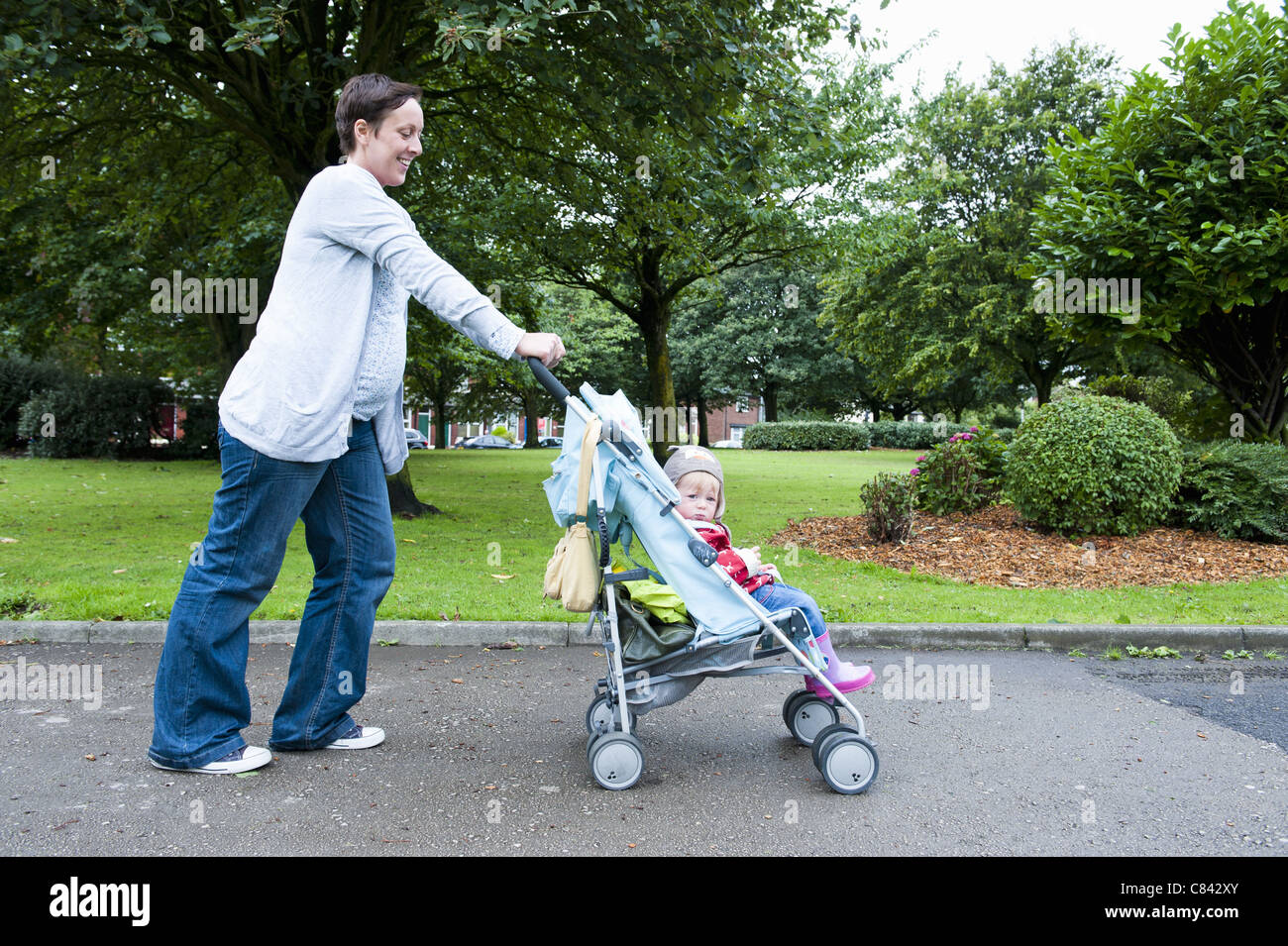 Mother pushing daughter in stroller Stock Photo - Alamy