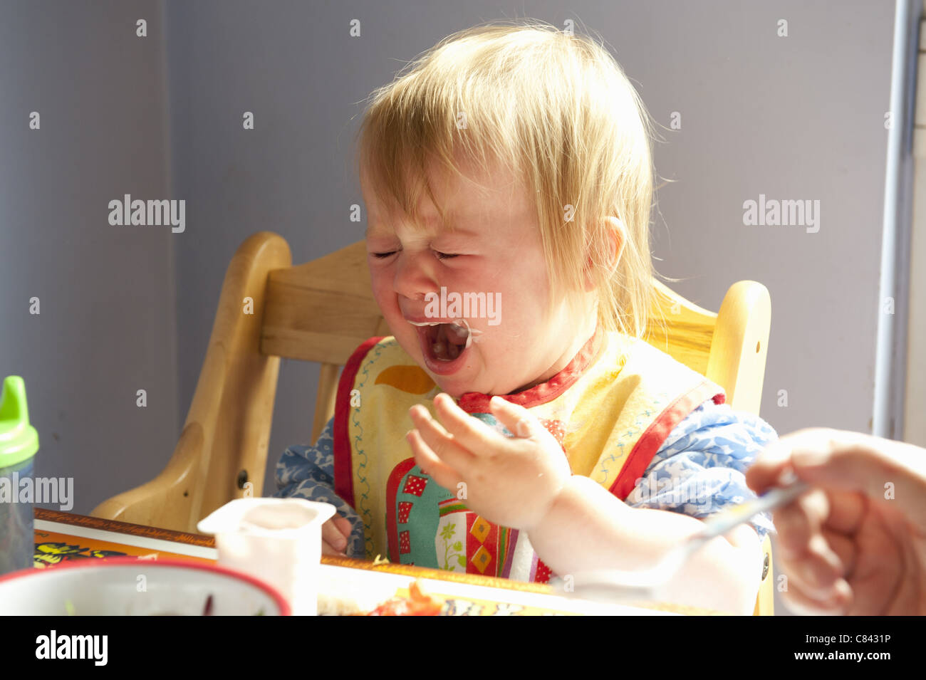 Toddler girl crying at table Stock Photo - Alamy